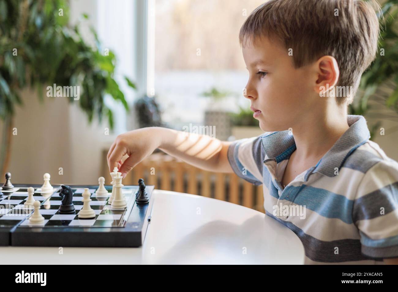 Children brothers play chess at home at a round white table in the ...