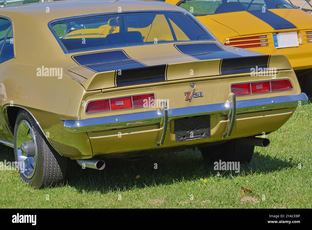 Restored gold chevrolet camaro z28 with black racing stripes is parked ...