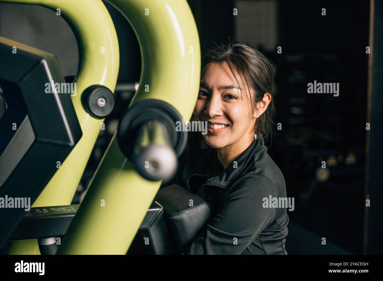 Portrait of beautiful Asian young woman performing squats on a gym ...