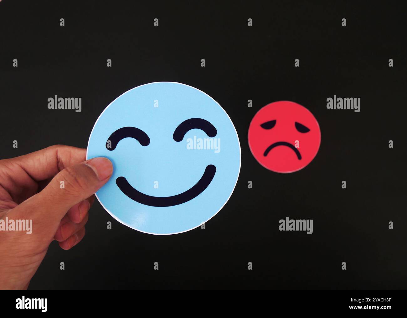 Hand holding card sad face hiding behind happy face. Concept of mood ...