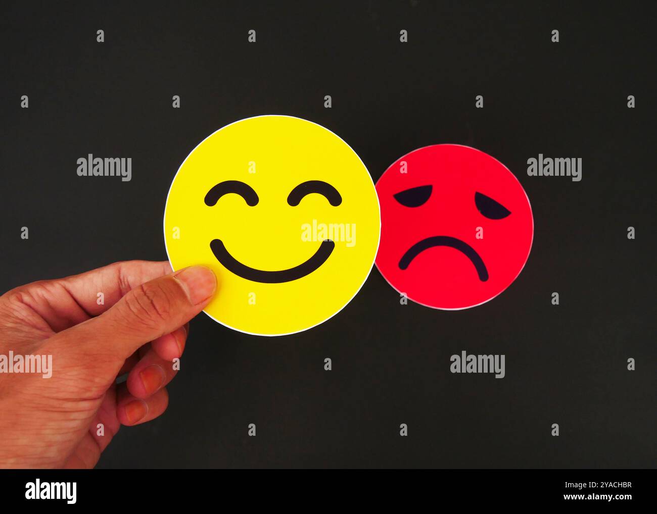 Hand holding card sad face hiding behind happy face. Concept of mood ...