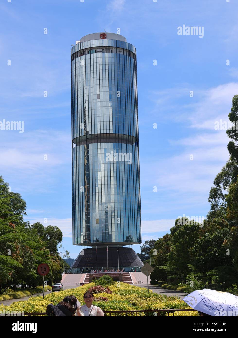 Tun Mustapha Tower with a glass facade and a large umbrella being held ...