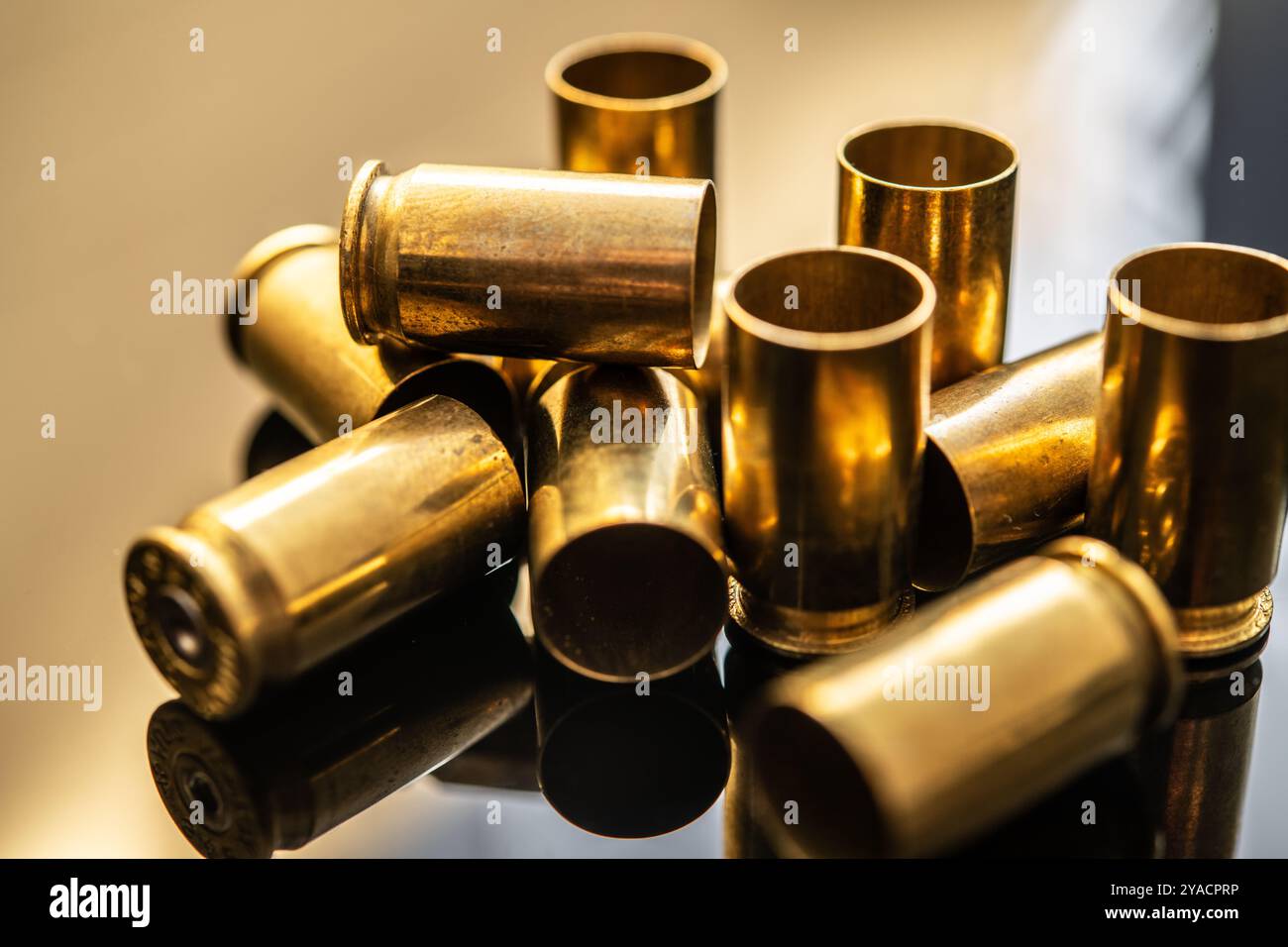 Close-up view of spent brass bullet casings on a reflective surface ...