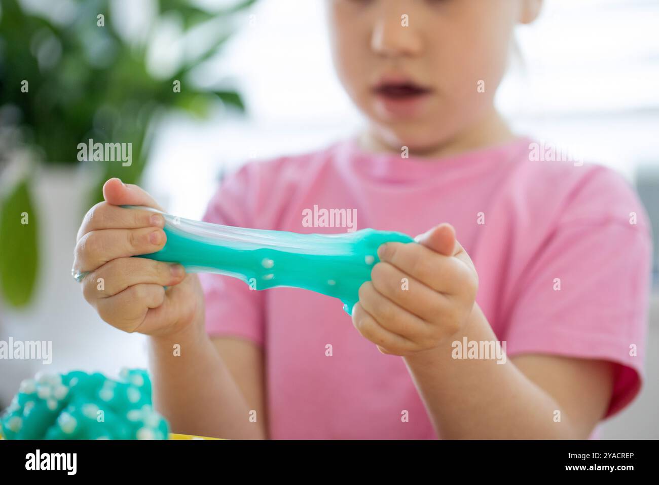 A child playing with bright, blue slime, enjoying a fun and creative ...