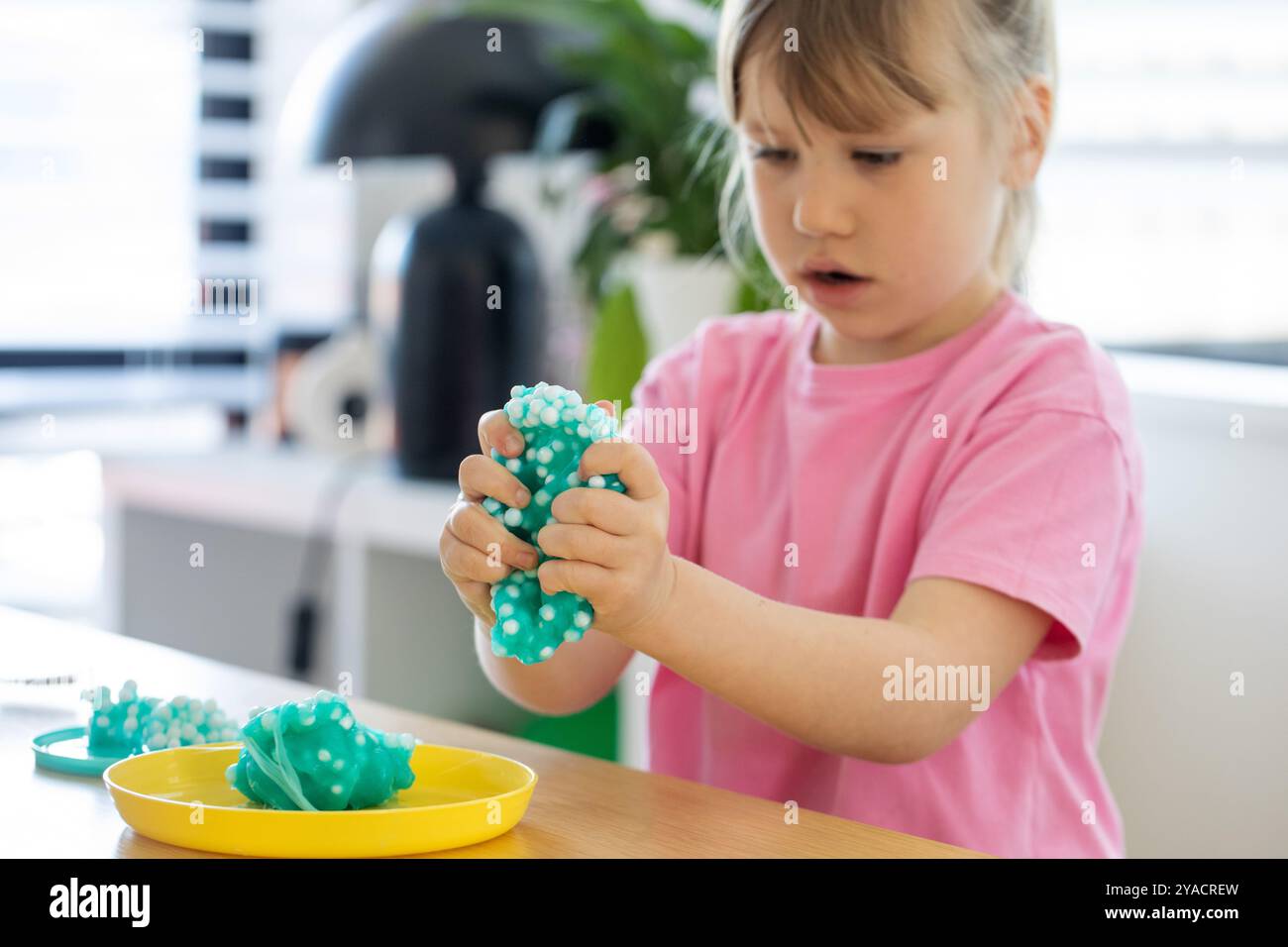 A cute girl playing with bright, blue slime, enjoying a fun and ...