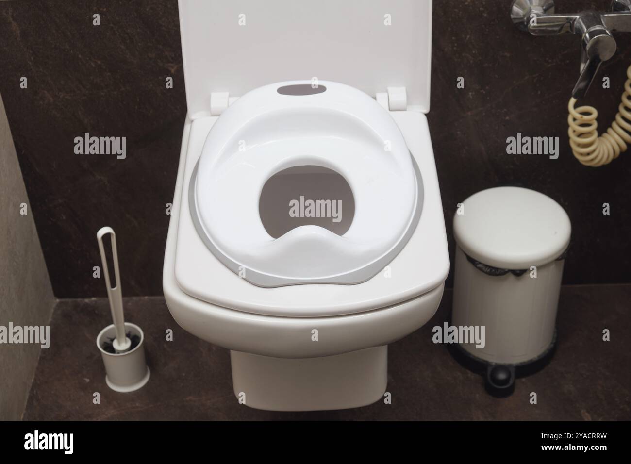 Toilet with white potty baby training seat, toilet brush, and trash bin ...