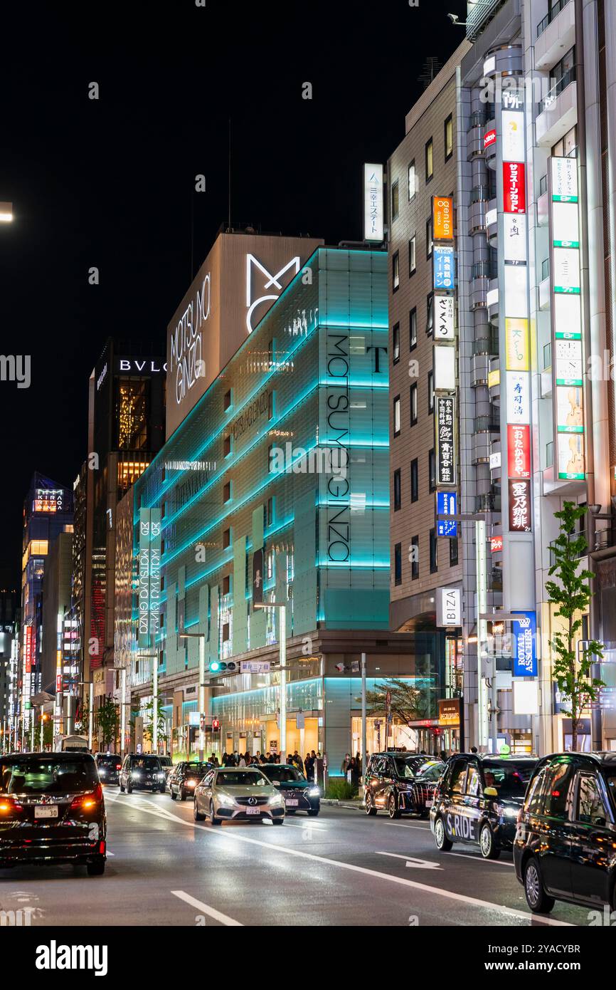 Ginza busy with taxicabs and cars driving in front of the green ...