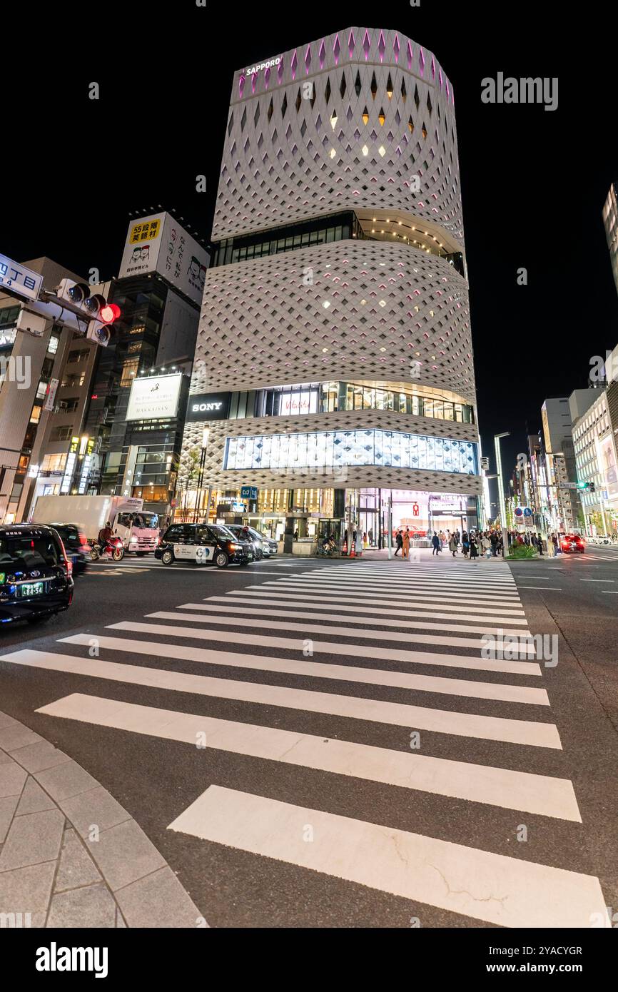 Empty pedestrian crossing leading to the illuminated white clad landmark Ginza Place building at ...
