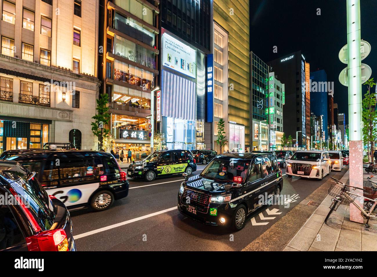 View along the Ginza street in the evening with many taxicabs driving ...