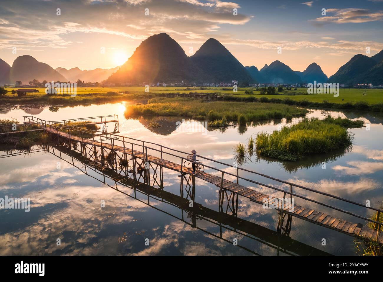 Rural scene of sunset shines over mountain with villager pushing ...
