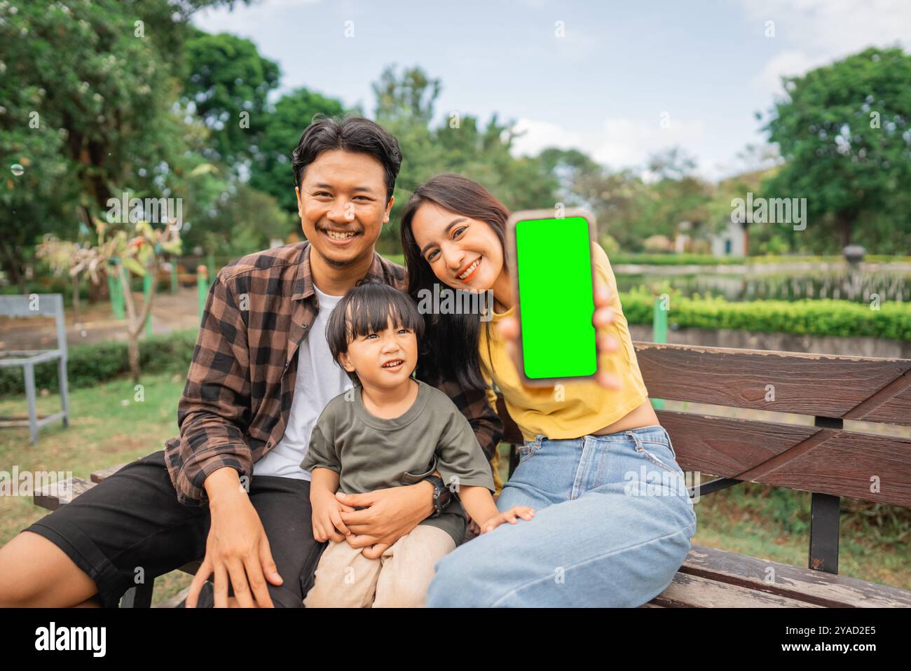 young mother shows phone screen while sitting with husband and little ...