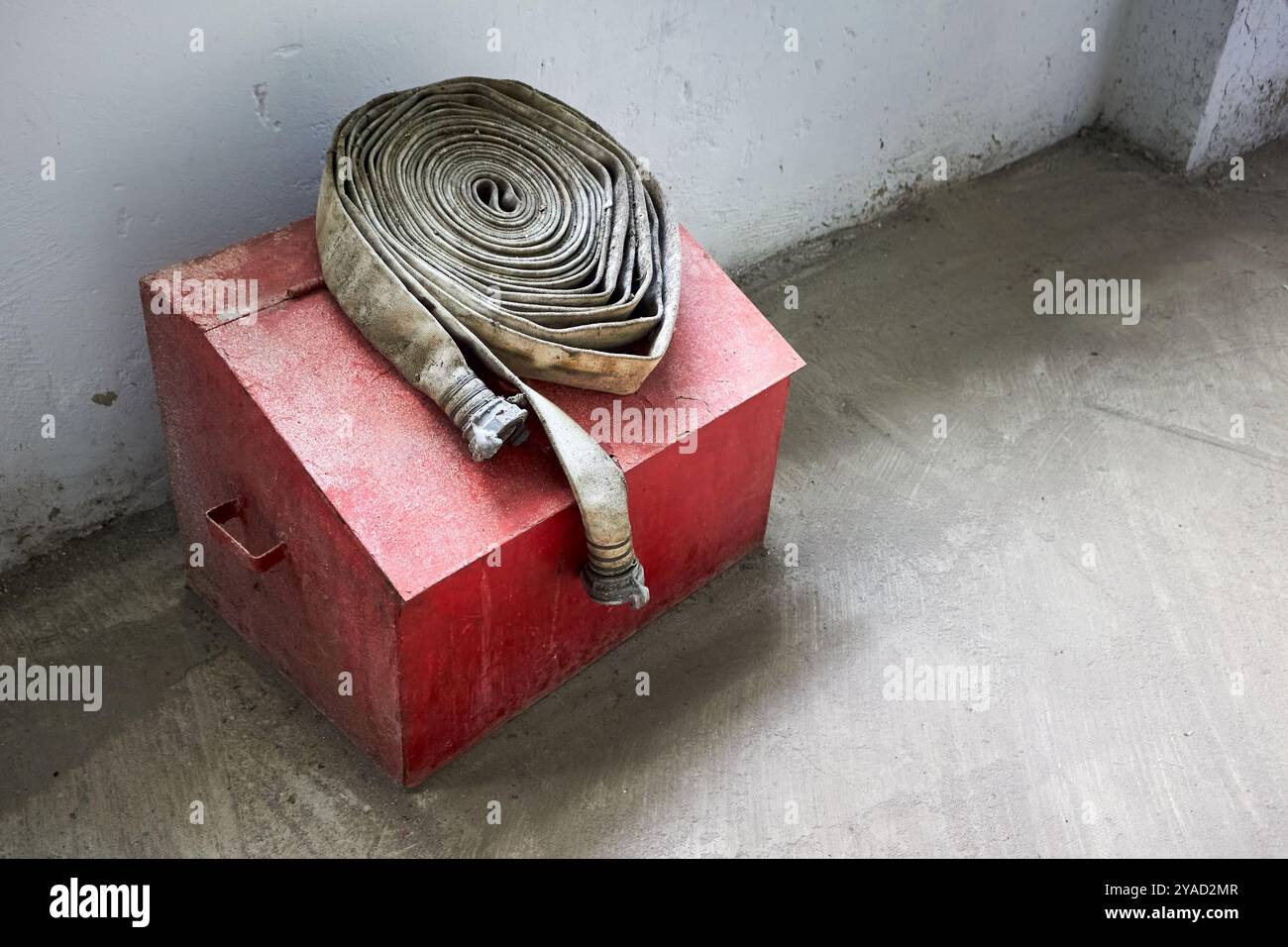 Fire hose old faded condition on red fire box with sand inside ...
