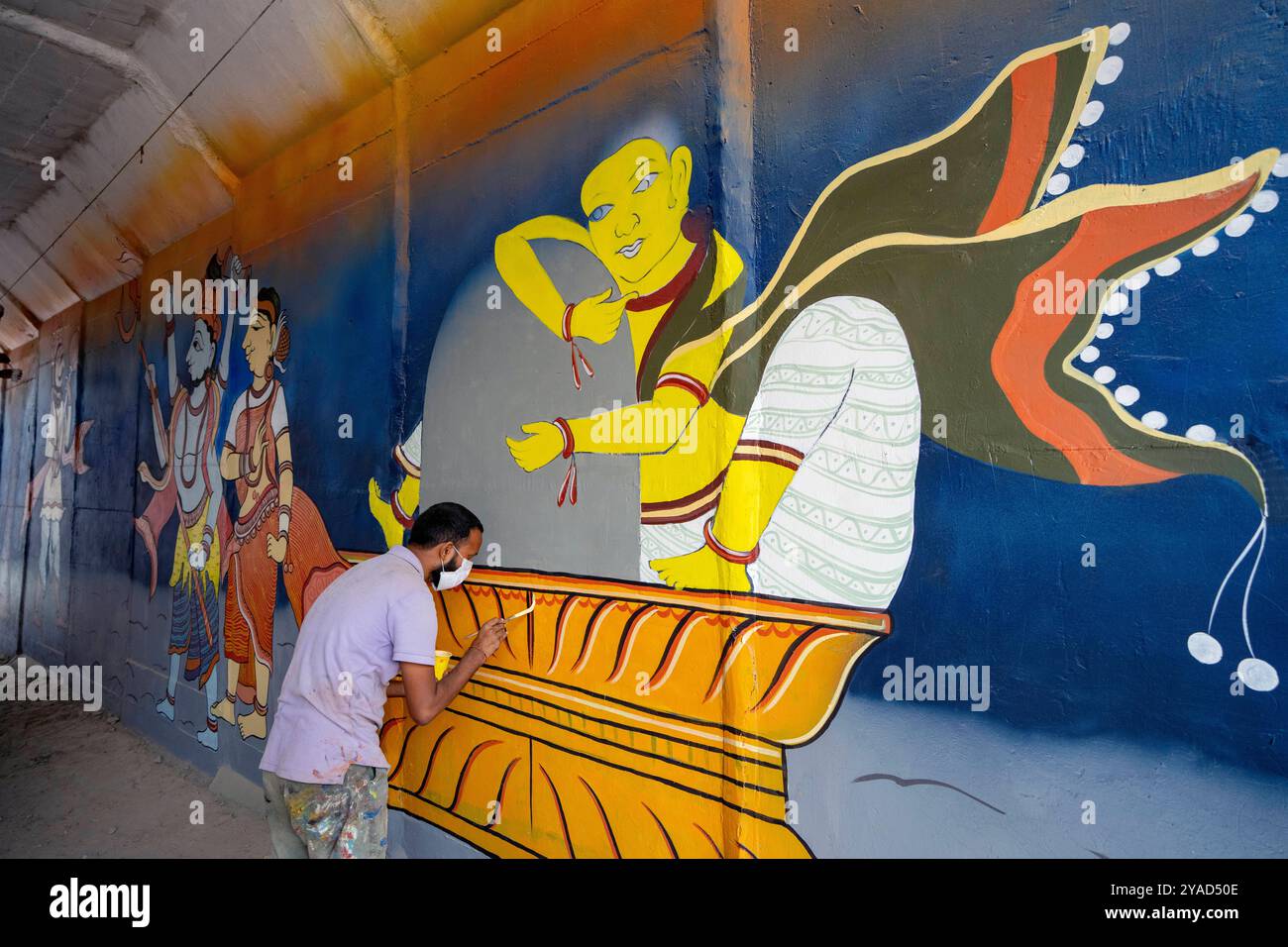 An Indian artist paints under the railway bridge bypass during the ...