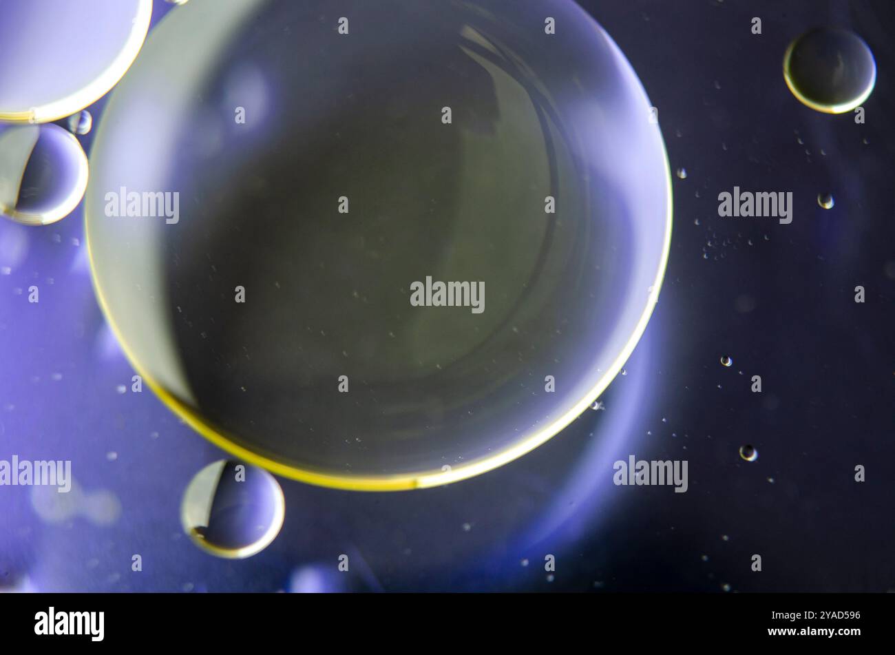 Close-up of iridescent oil streaks on water, with a smooth dark ...