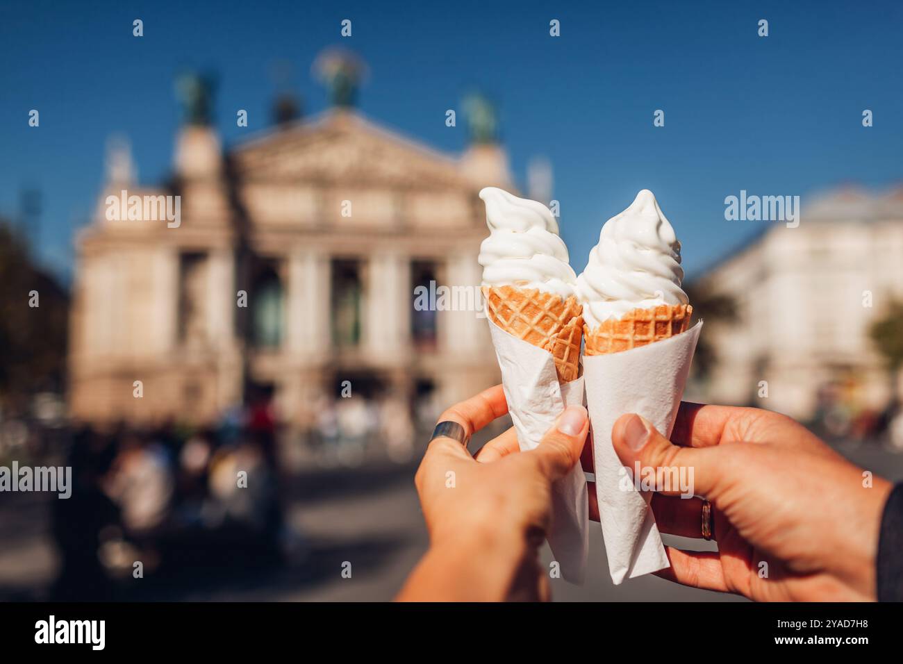 Close up of two cones of ice cream in couple's hands. People eating ...