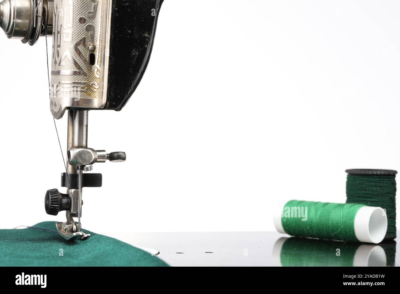 Sewing machine with green fabric and spools of threads isolated on ...