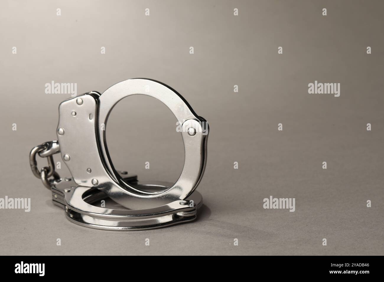 Metal chain handcuffs on light grey background, closeup. Space for text ...