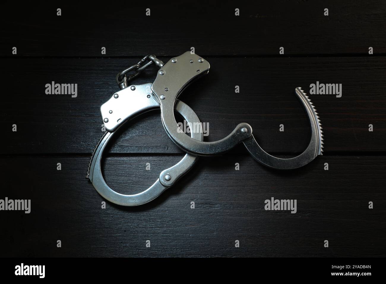 Metal chain handcuffs on black wooden table, top view Stock Photo - Alamy