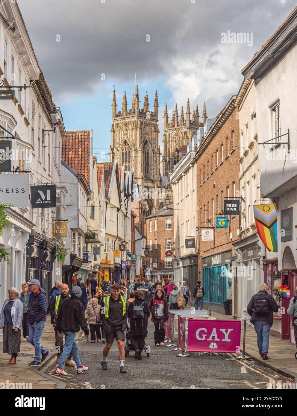 Historic city street lined with shops and the towers of a cathedral ...