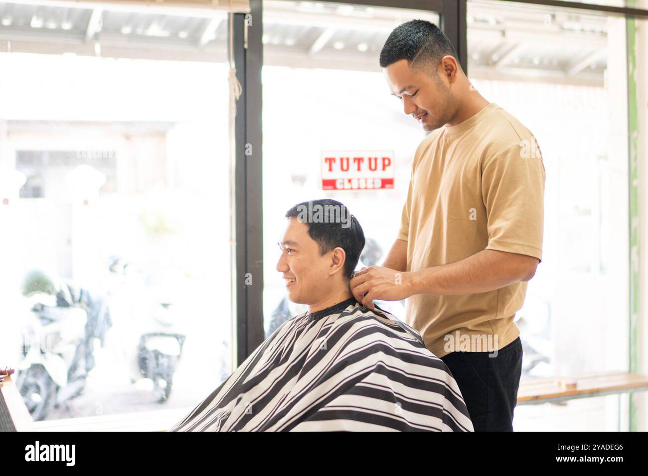 A man is currently getting his hair cut by a barber in a barber shop ...