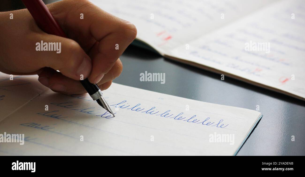 Detail of a child's left hand writing the syllables li and le with a ...