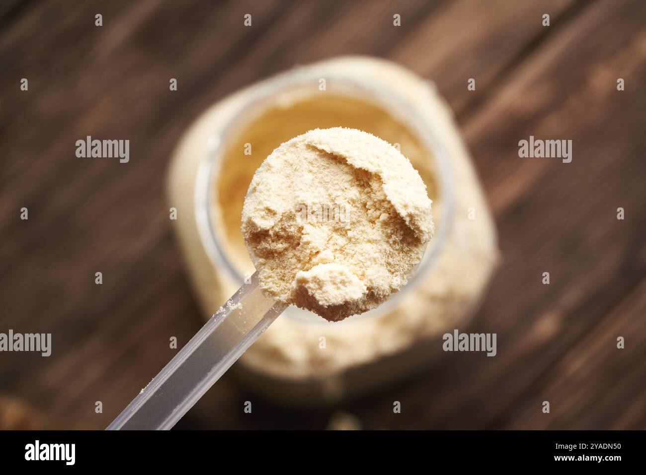 Whey protein powder in a measuring scoop above a jar Stock Photo - Alamy