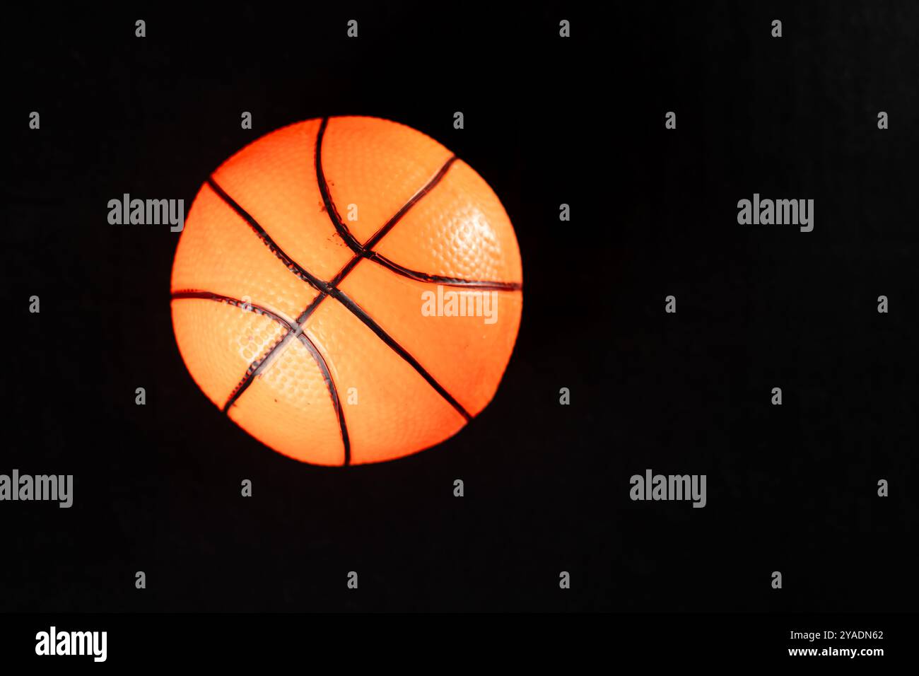 A close-up of an orange basketball resting on a black surface, with a ...