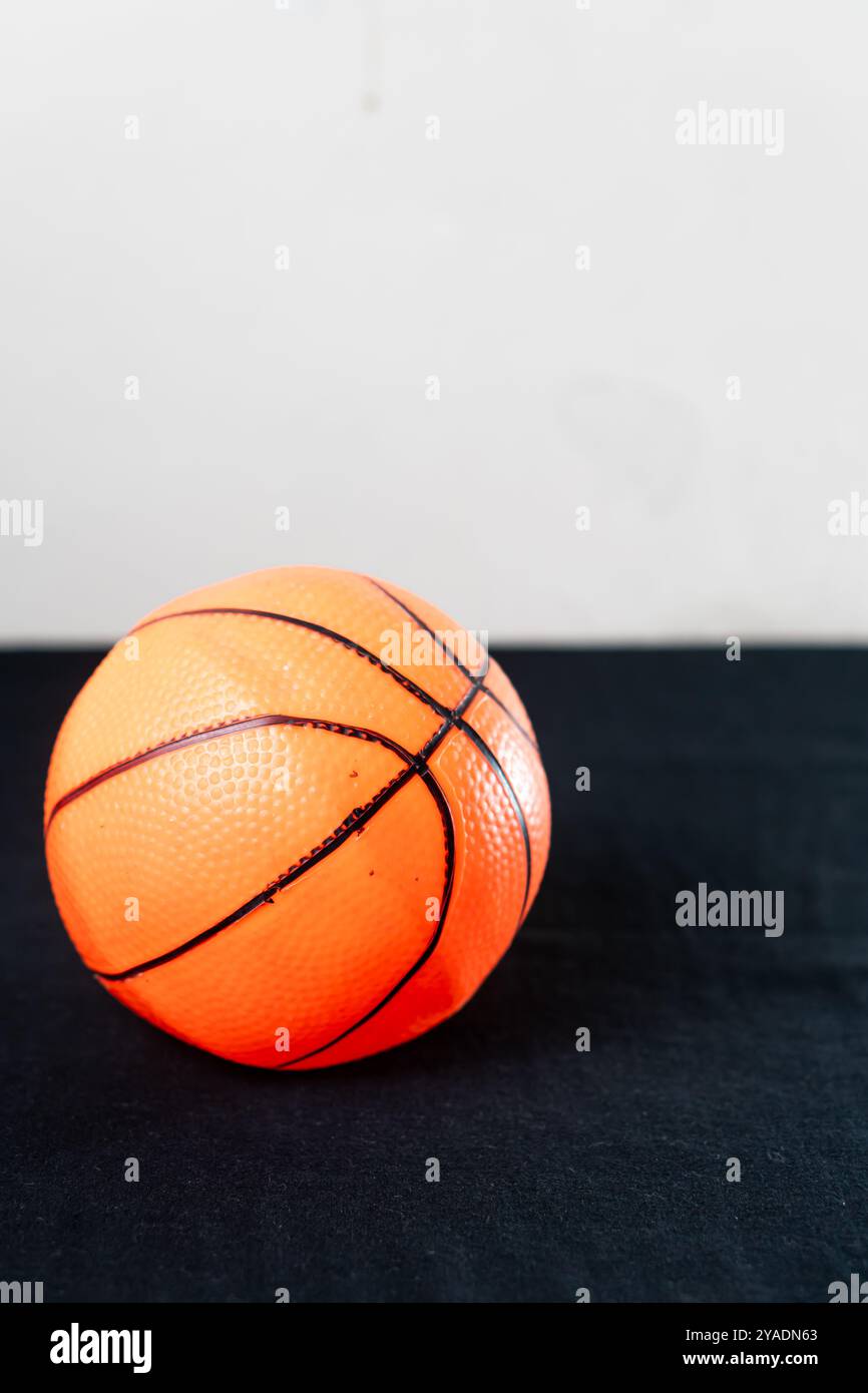 A close-up of an orange basketball resting on a black surface, with a ...