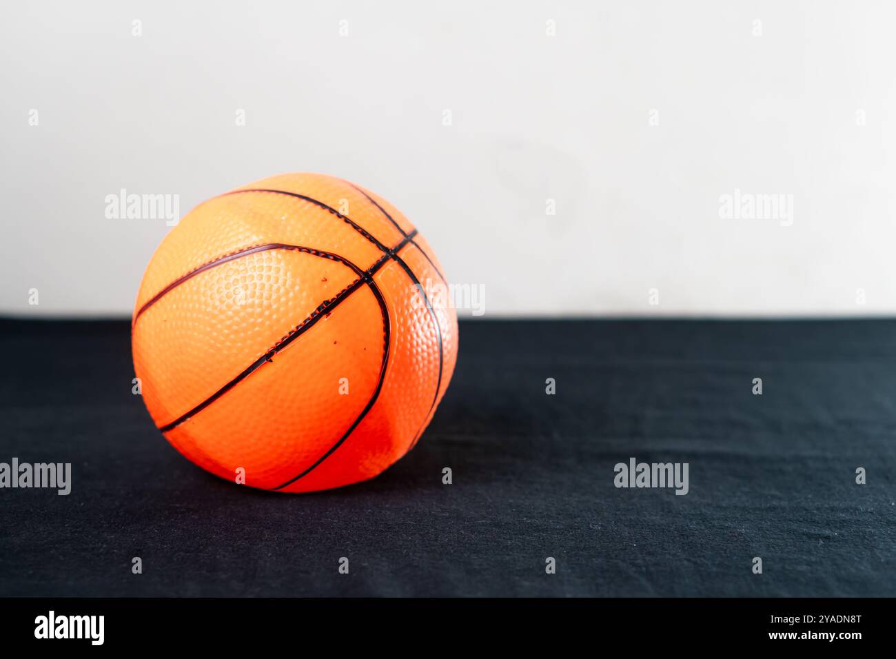 A close-up of an orange basketball resting on a black surface, with a ...