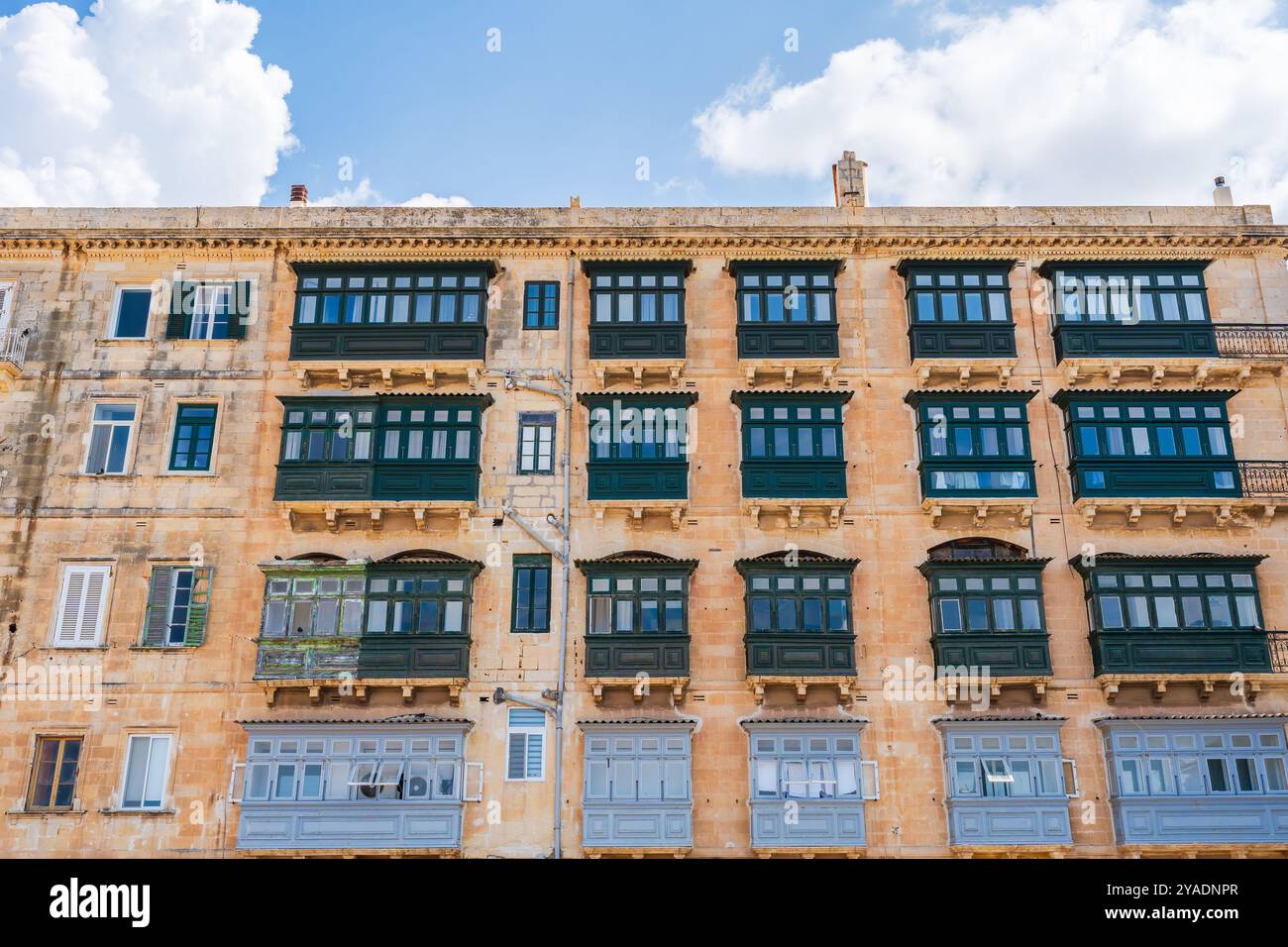 Upward view of the traditional Maltese buildings with green balconies ...
