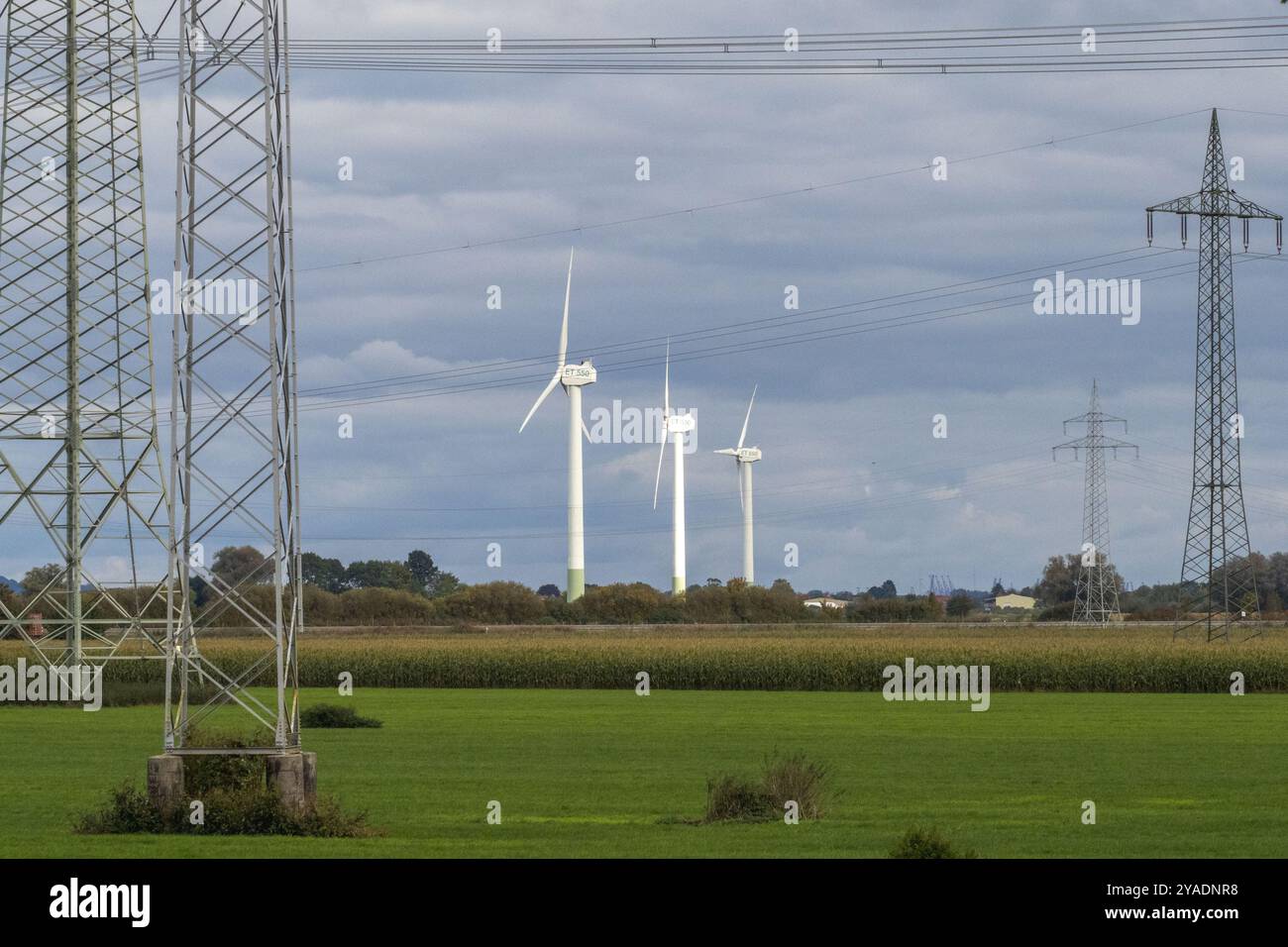 three wind turbines in between the power lines Stock Photo - Alamy