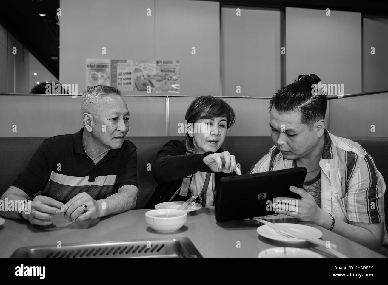 Vietnamese family reading menu at restaurant. Family of 3 looking at ...