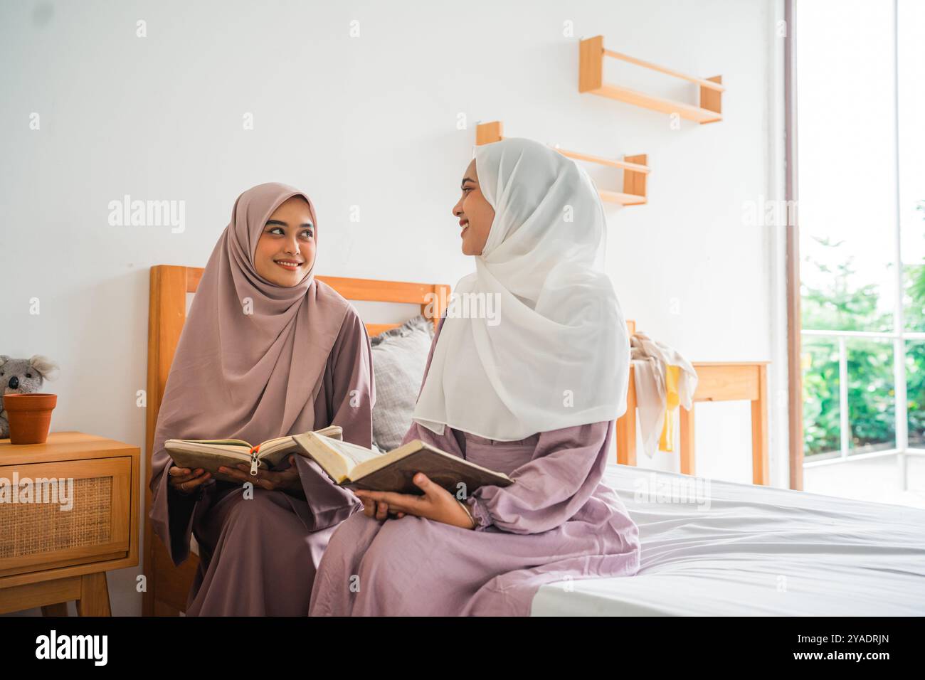 Two Muslim women in hijab chatting together and reading the Quran Stock ...