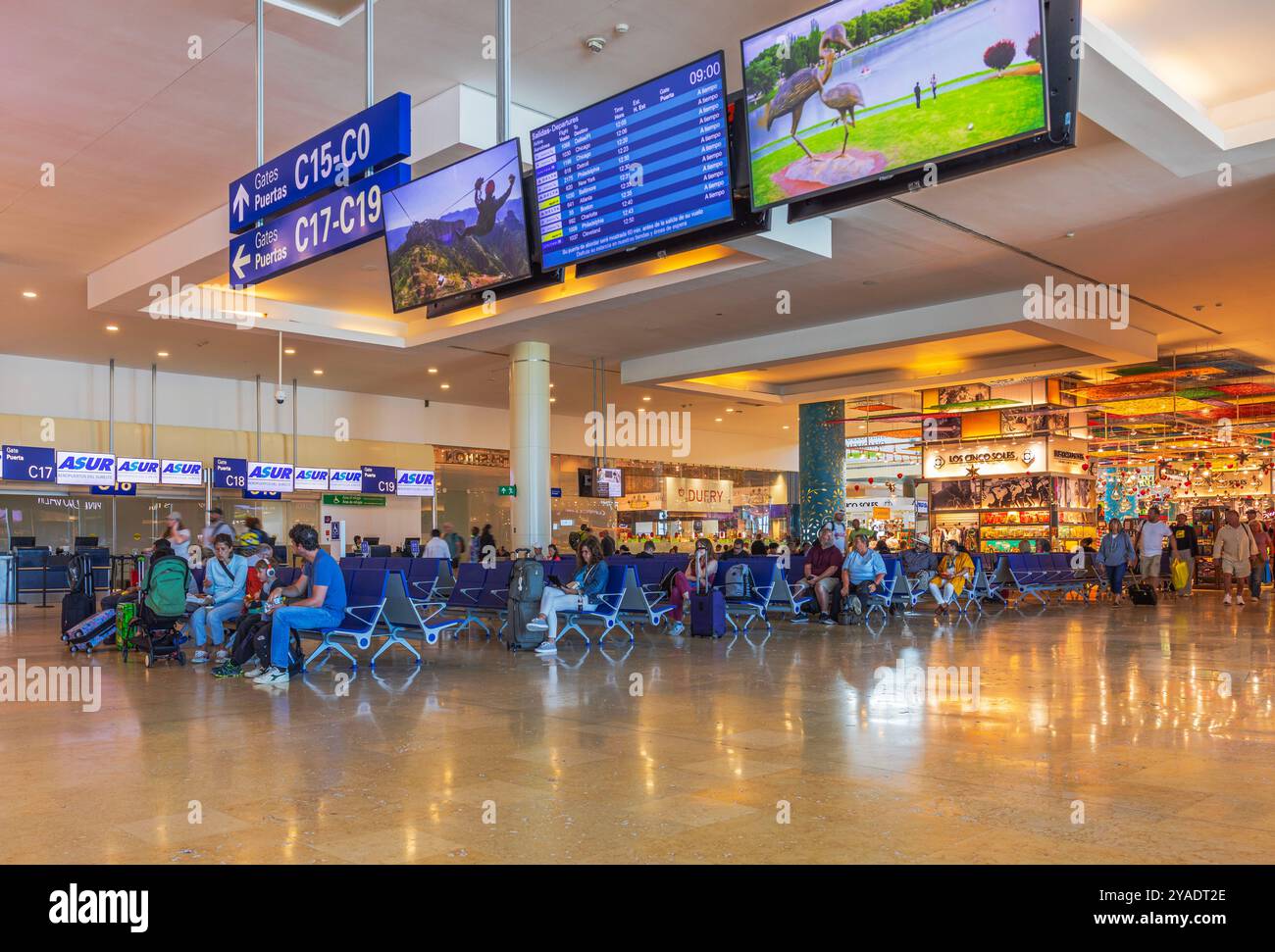 Busy waiting area in International Airport with travelers seated near ...