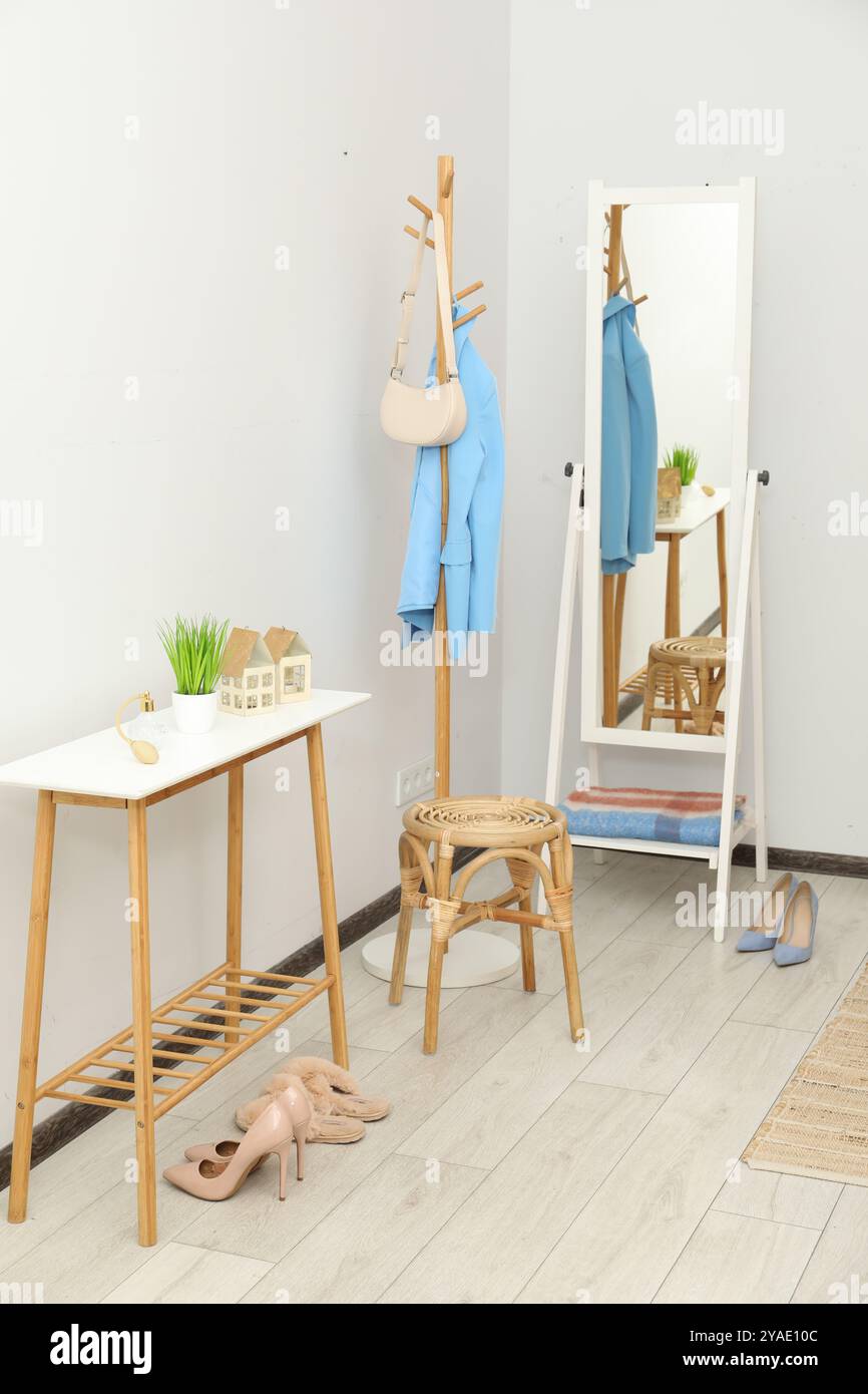Clothing rack, mirror, storage bench and clothes in hallway Stock Photo ...