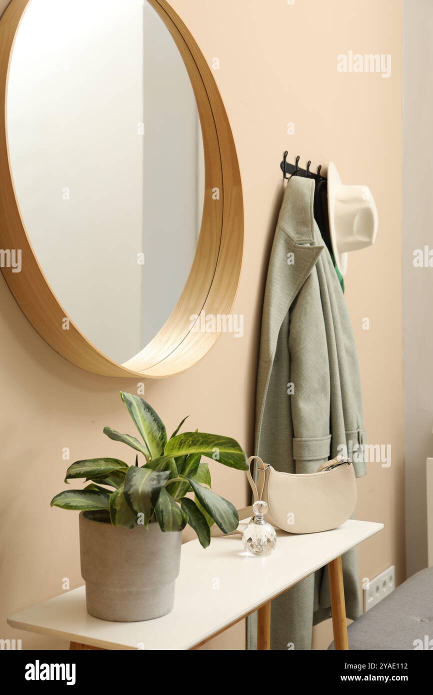 Coat rack with clothes, mirror and storage bench in hallway. Interior ...