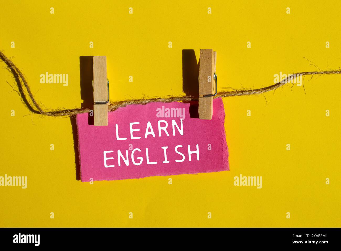 Learn english message written on ripped pink paper piece with yellow background. Conceptual ...