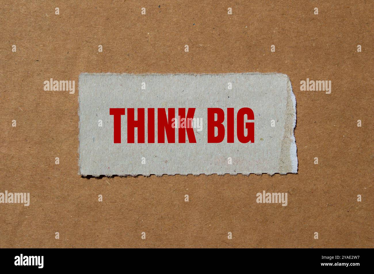 Think big message written on ripped torn paper piece with cardboard ...