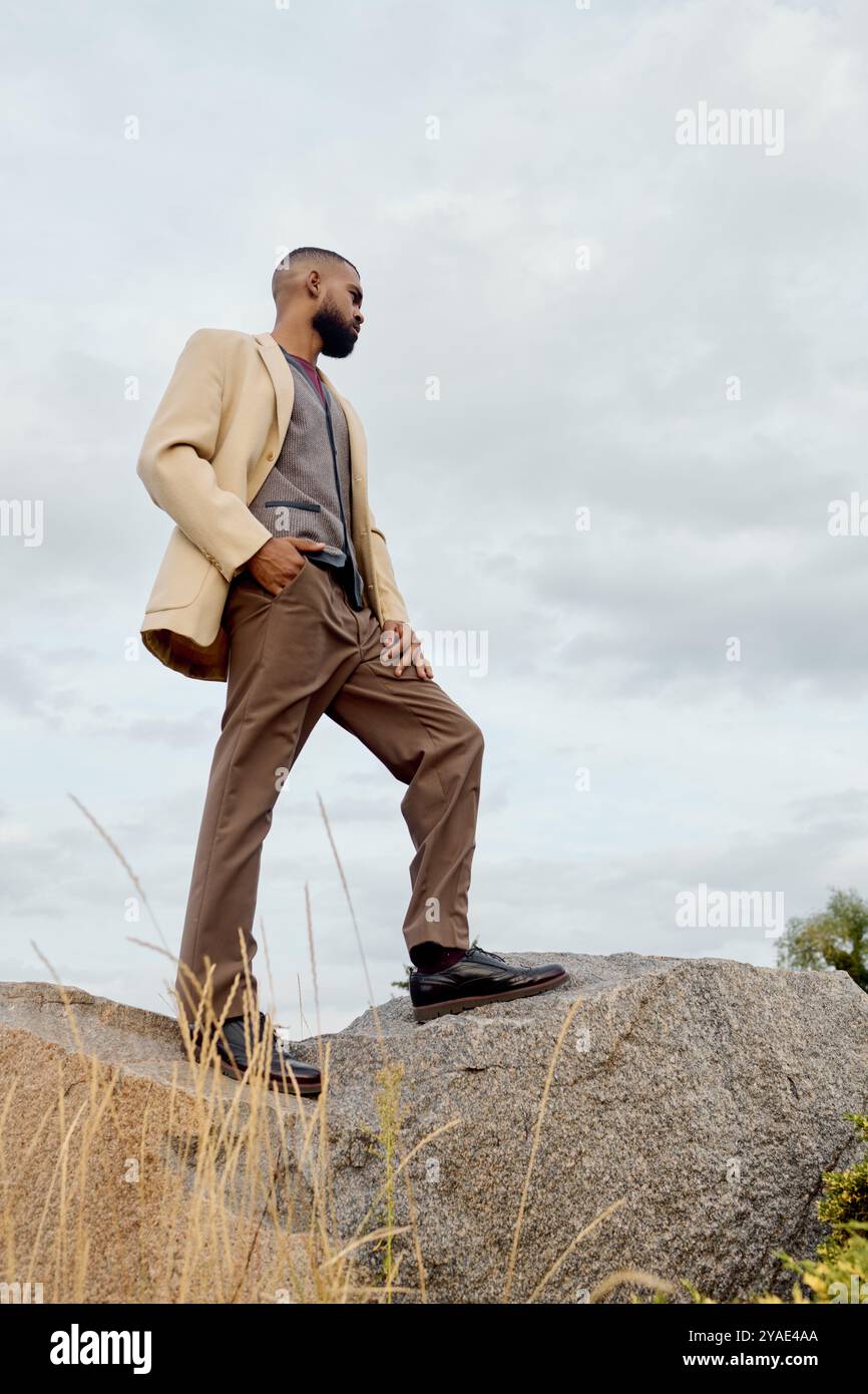 A dapper gentleman stands atop a rock, showcasing autumn fashion while ...