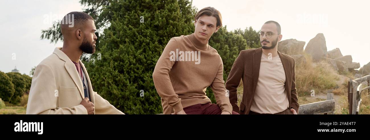 Three handsome men dressed in fall attire share a relaxed moment in a ...