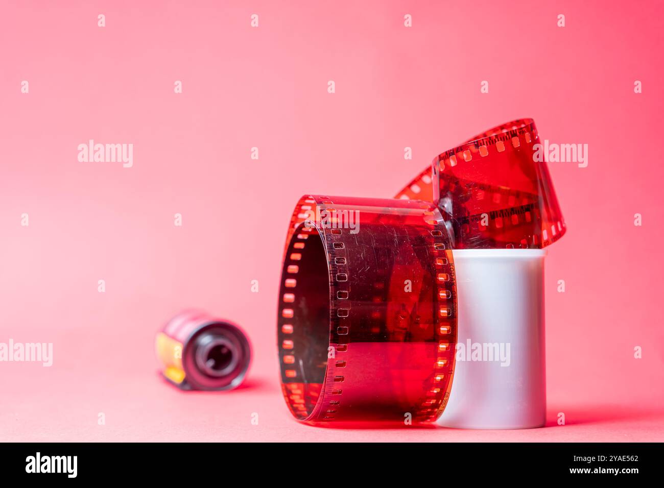 A close-up of a film reel with a strip of red film unwinding against a ...