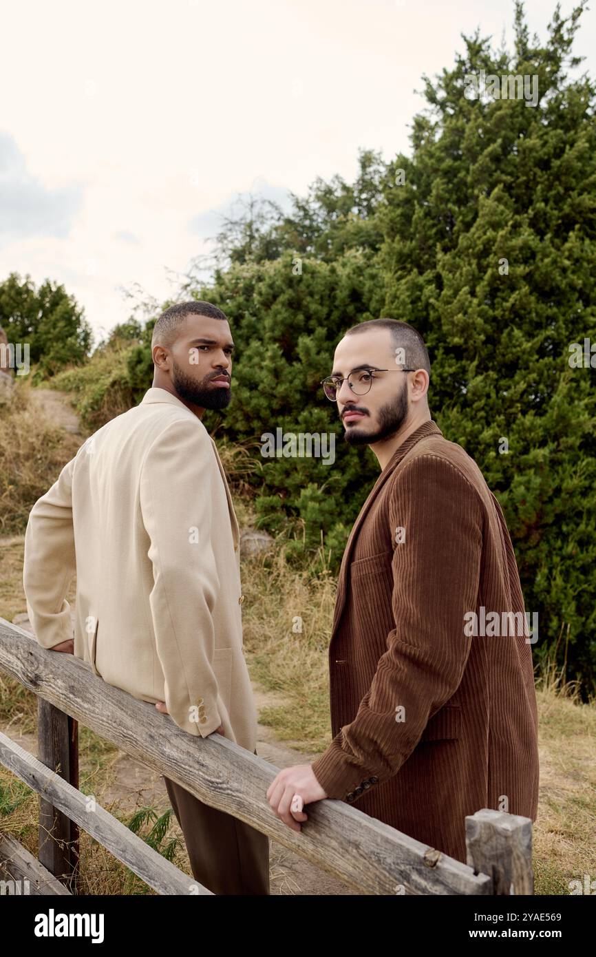 Two handsome men pose confidently in trendy fall attire amidst a serene ...