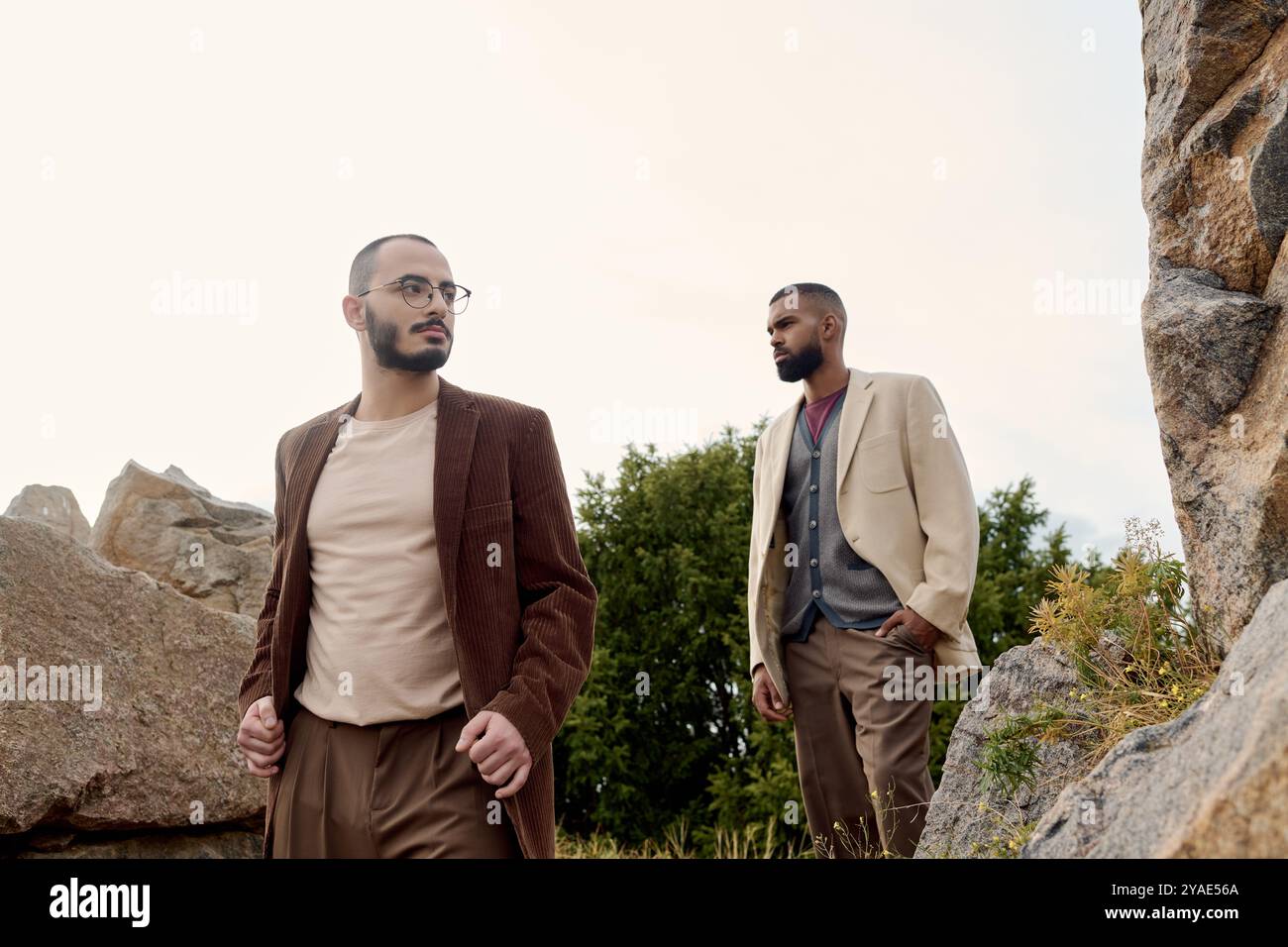 Two handsome men in chic autumn outfits stroll through a serene natural ...