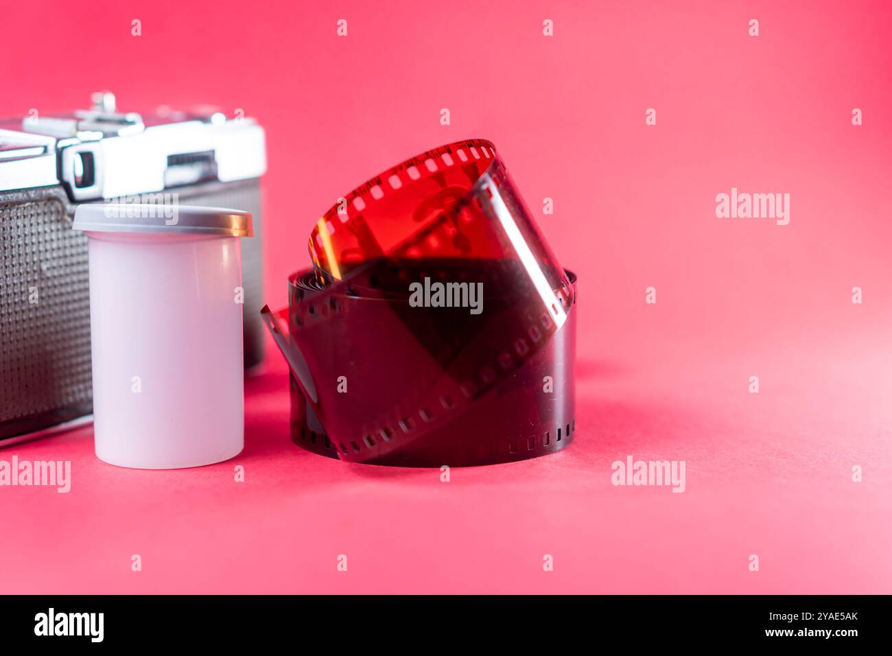 A vintage camera with a roll of film and a film canister on a bright ...