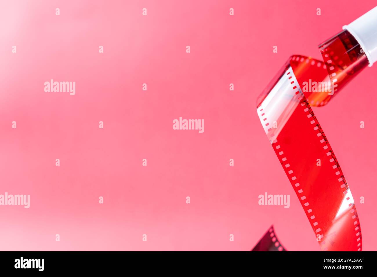 A close-up of a film reel with a strip of red film unwinding against a ...