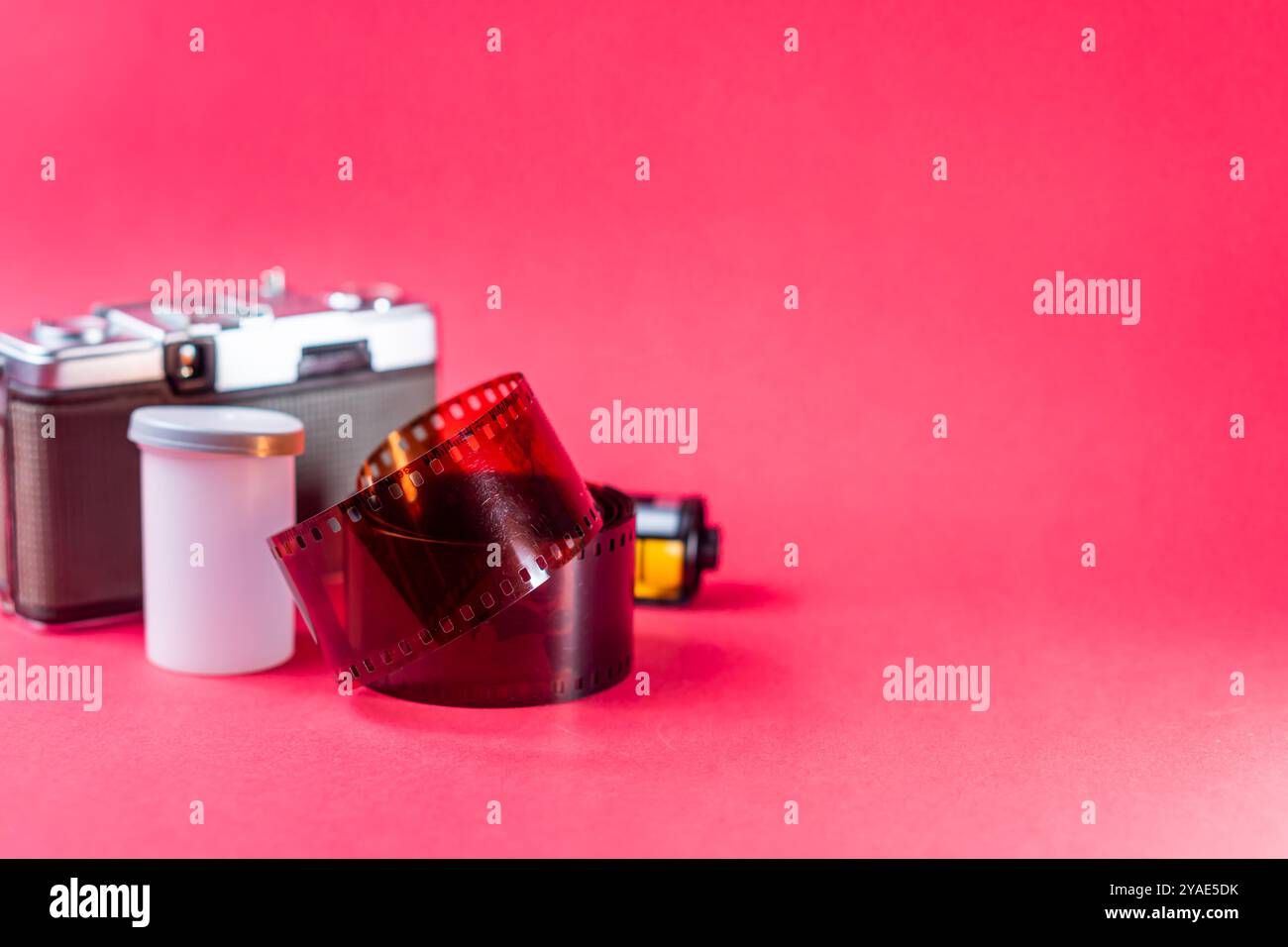 A vintage camera with a roll of film and a film canister on a bright ...