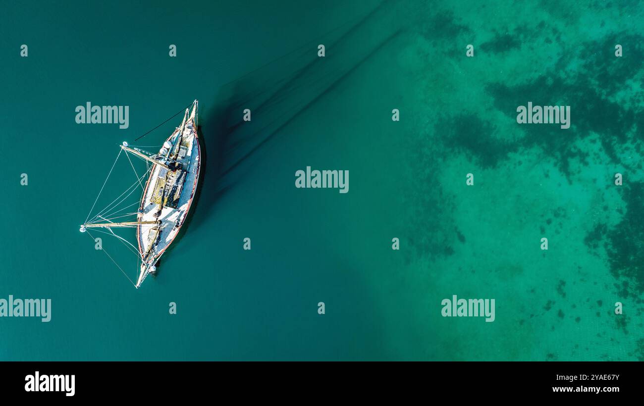 Aerial view of shadows from a boat's masts over clear blue water Stock ...