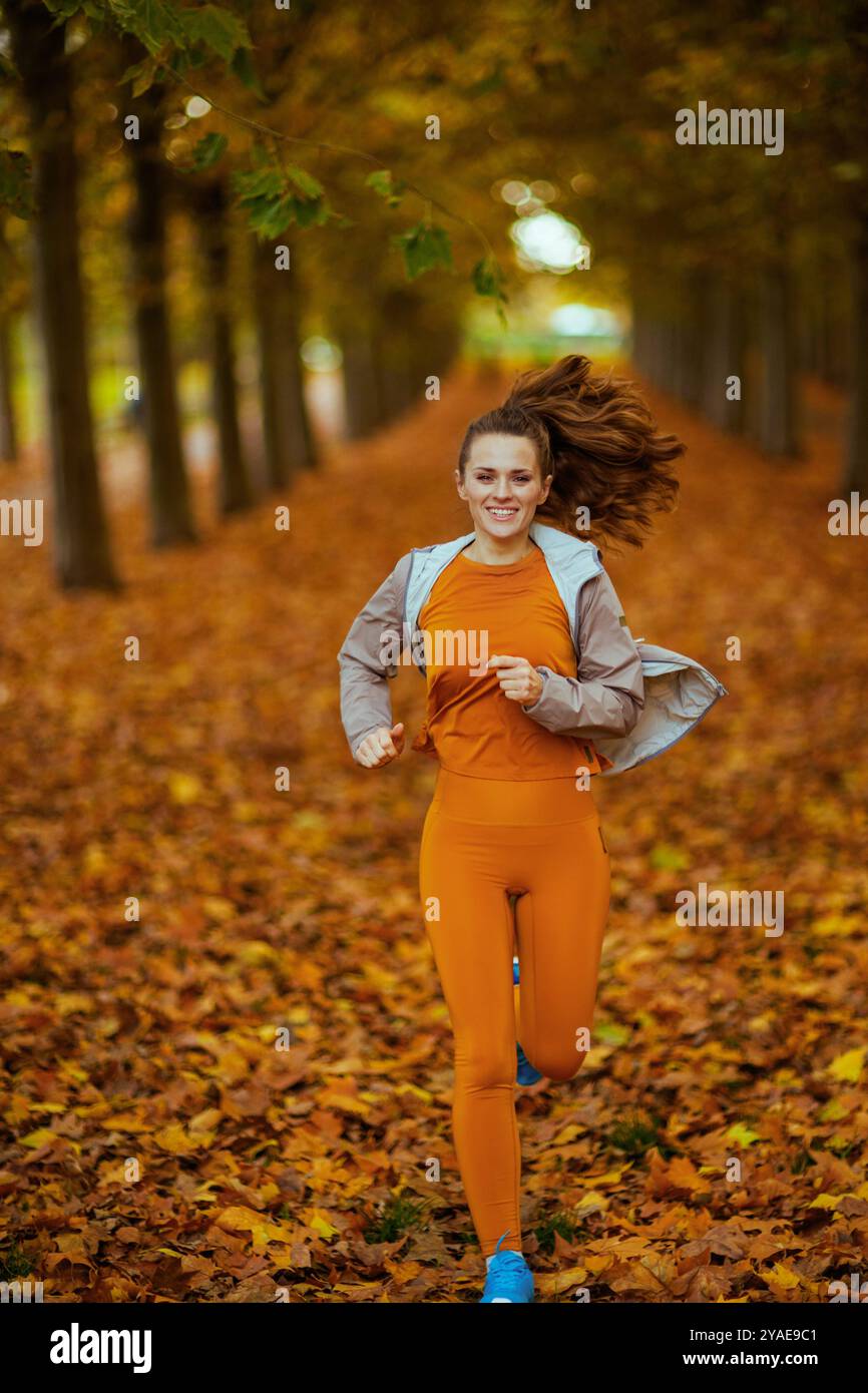 Hello autumn. happy modern woman in fitness clothes in the park running ...