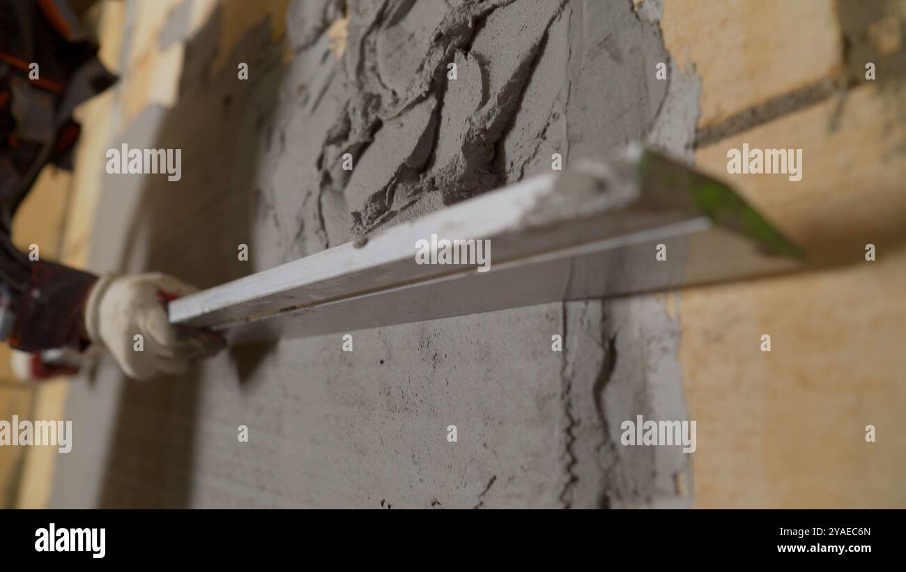 Construction worker using a spirit level while plastering a wall ...