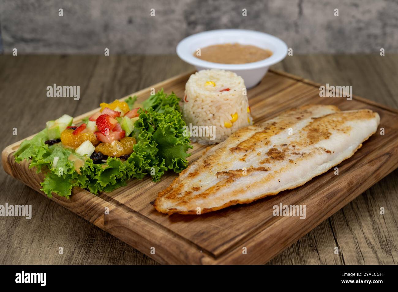 Grilled Basa fish fillet dinner served with rice and beans on a wooden ...
